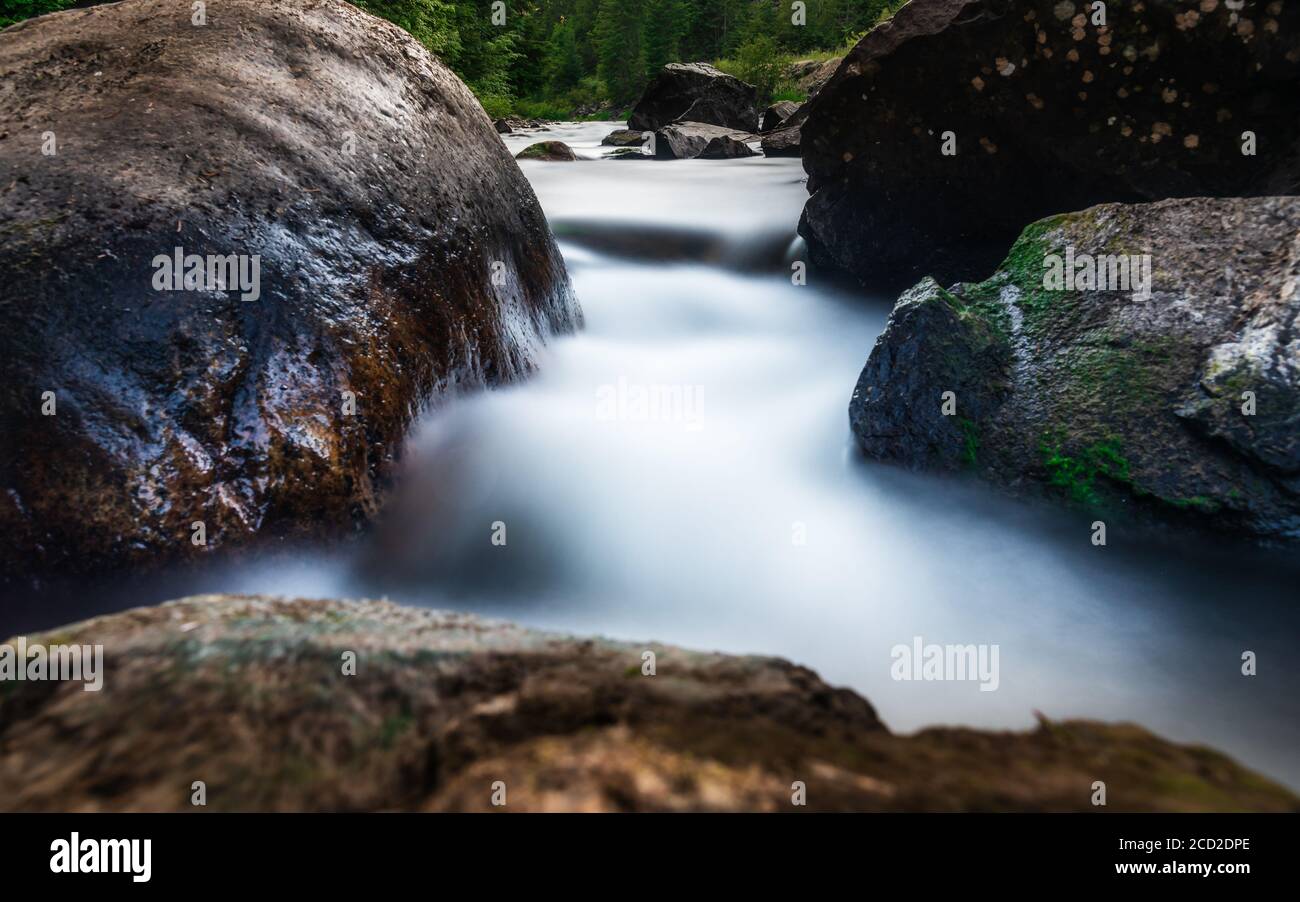 Smooth creek water flowing between the rocky canyon in Idaho panhandle ...