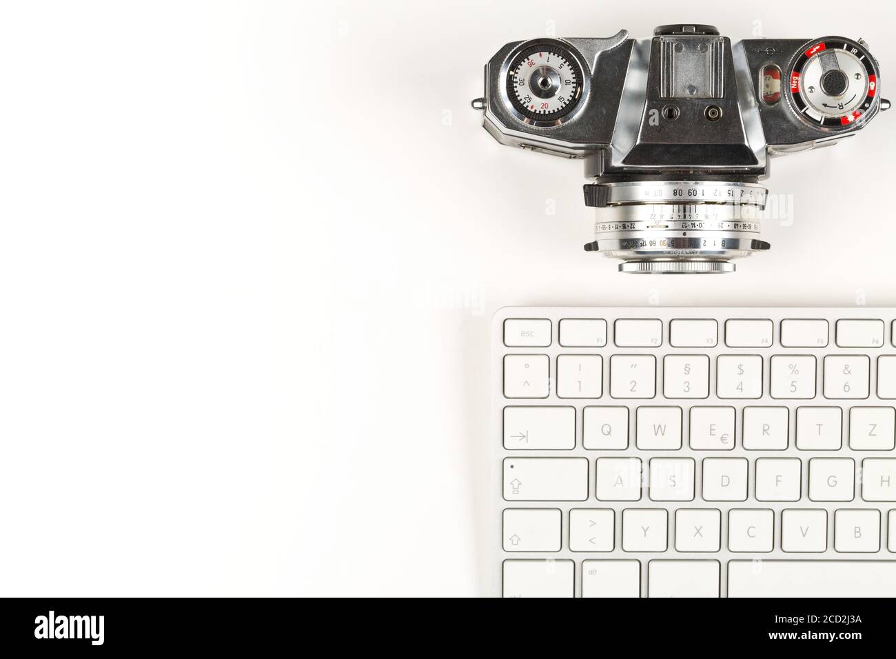 Retro analog SLR camera next to computer keyboard on white background ...