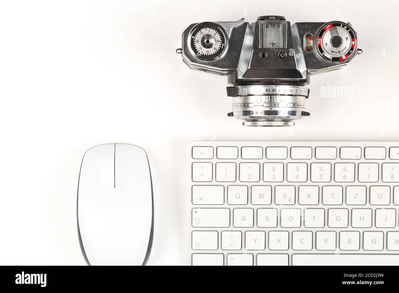 Retro analog SLR camera next to computer keyboard and mouse on white ...
