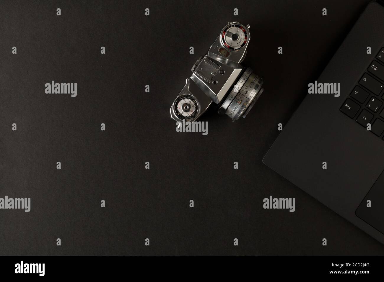 Retro analog SLR camera next to laptop on black desk in office, digital ...