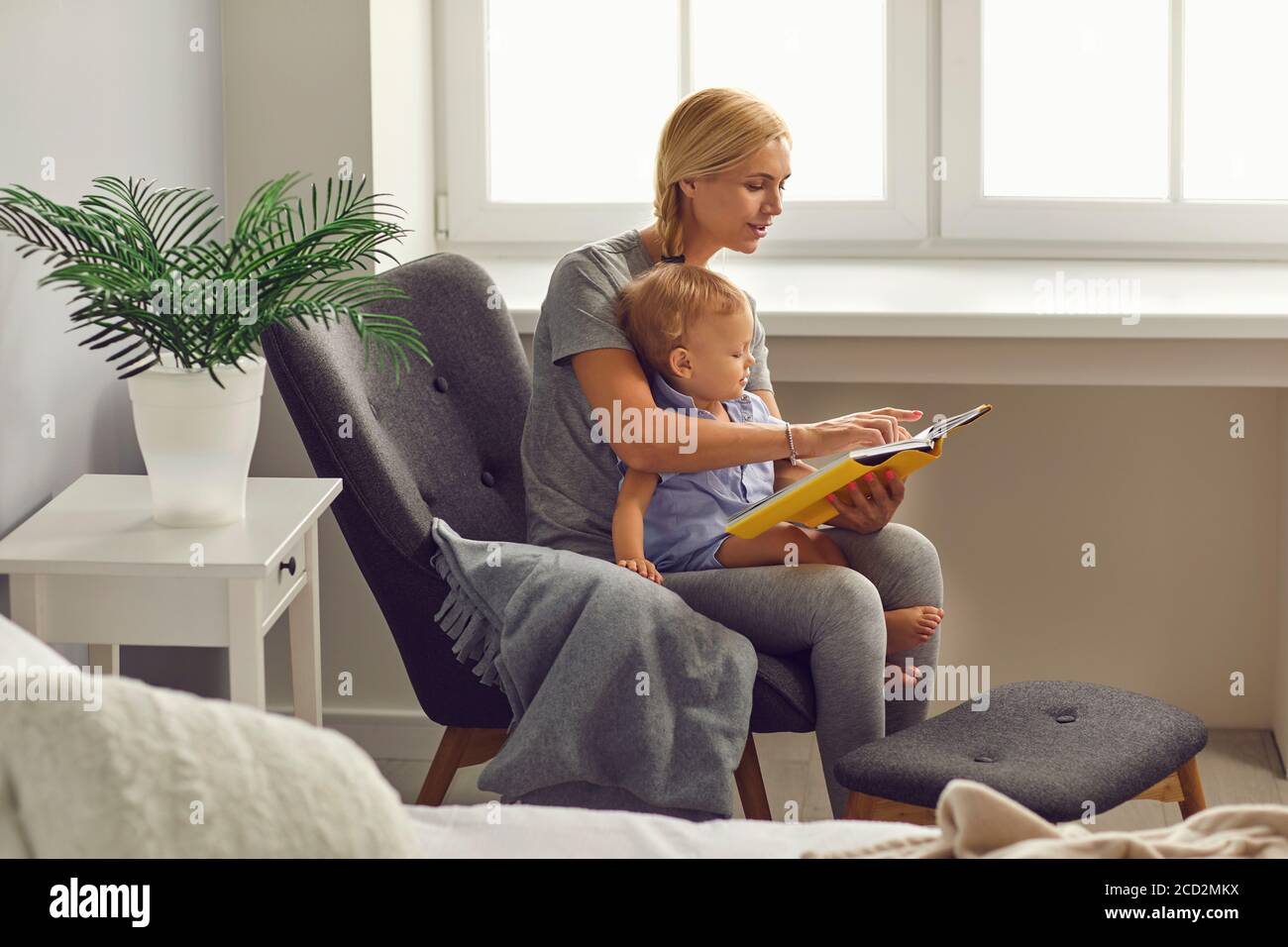 Mother and child Toddler reads a story in a book in a room with a ...