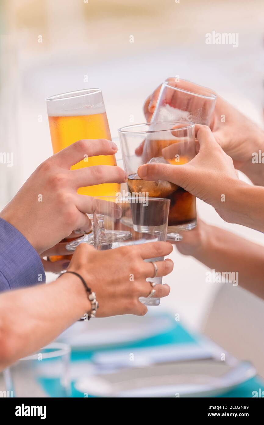 Close up of an assortment of hands doing a toast with different drinks ...