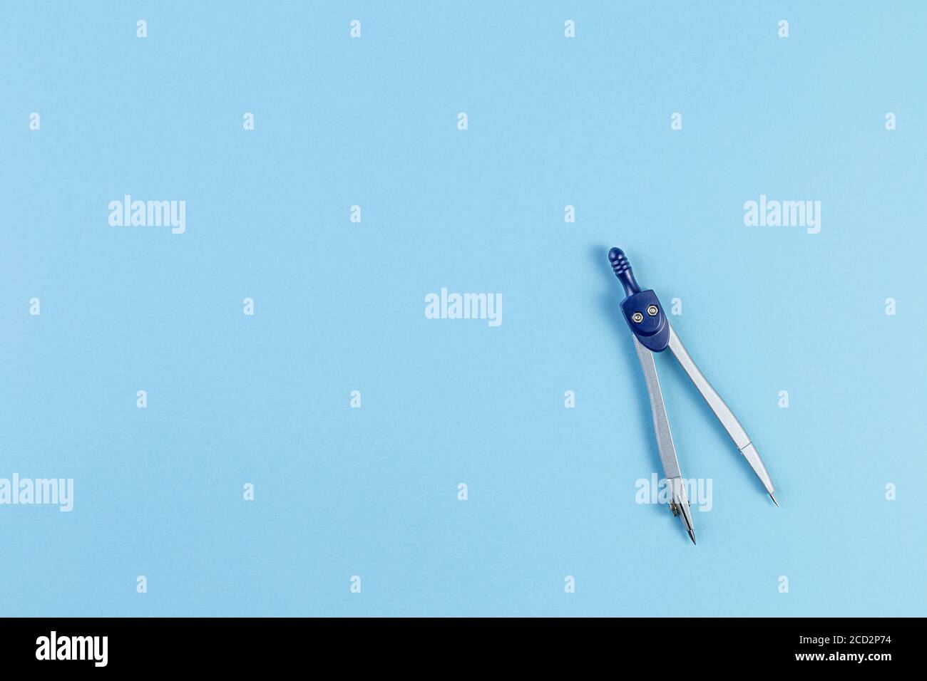 School compass for drawing circles in geometry. Isolated on blue paper ...