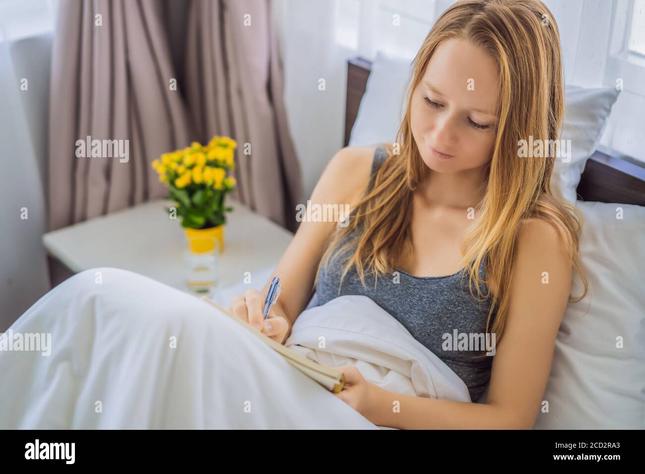 Woman writing diary or studying in bed thinking Stock Photo - Alamy