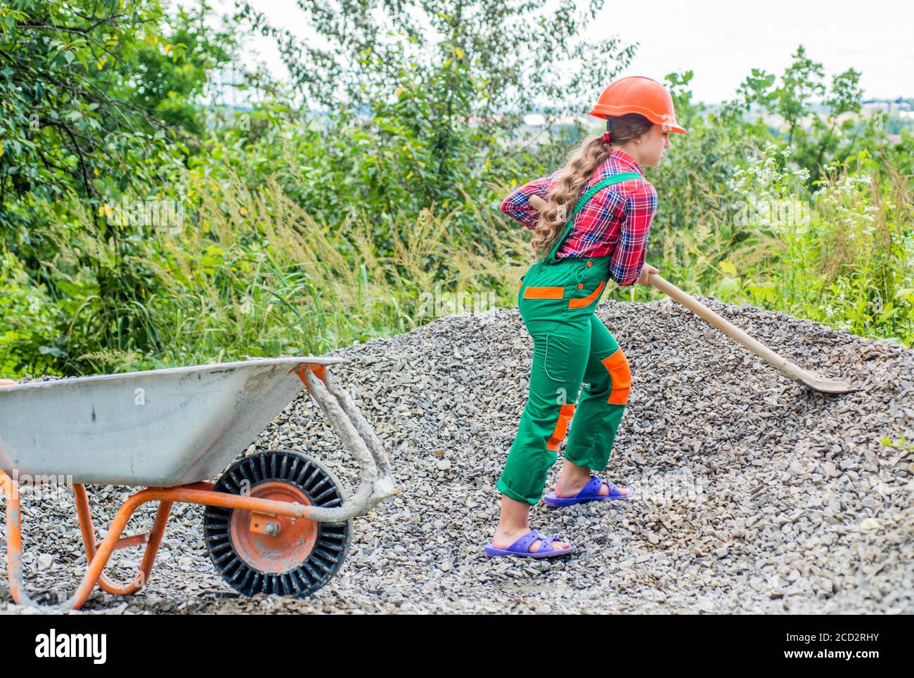 Outdoor activity. girl who is transporting rubble in a wheelbarrow ...