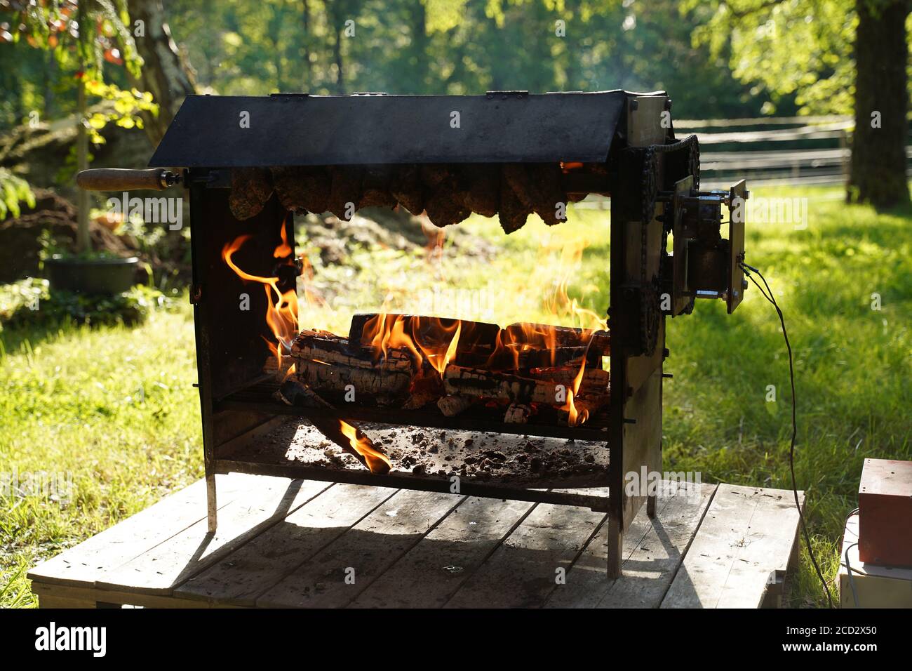 2 trussed chickens roasting over an open log fire Stock Photo - Alamy