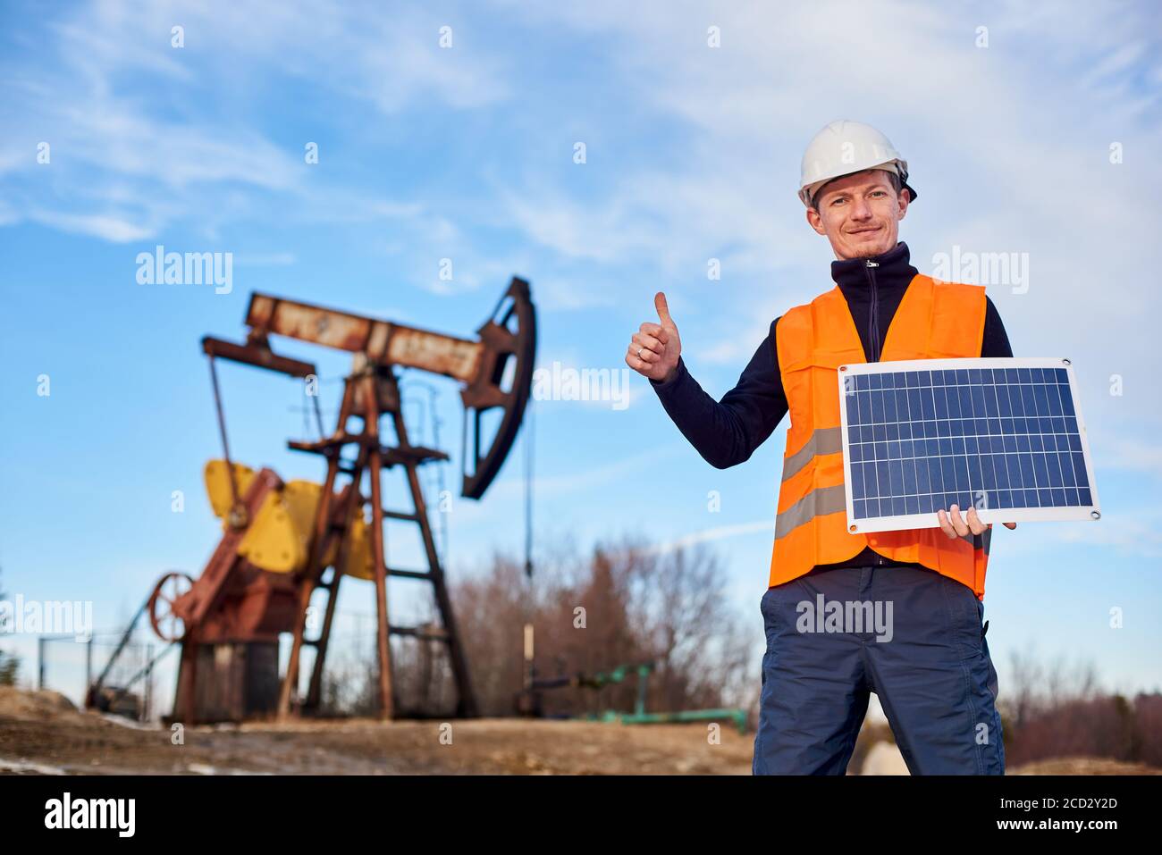 Portrait of smiling oil well operator in protective helmet, work vest ...