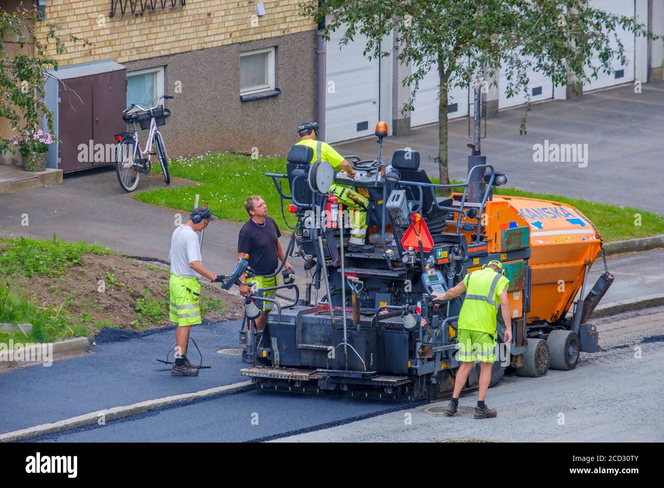 Asphaltic concrete laying machine in operation with workers Stock Photo ...