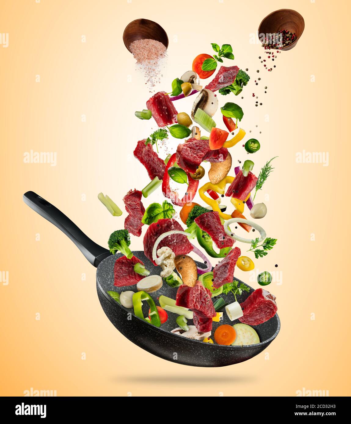 Fresh vegetables and pieces of beef meat flying into a pan, isolated on ...