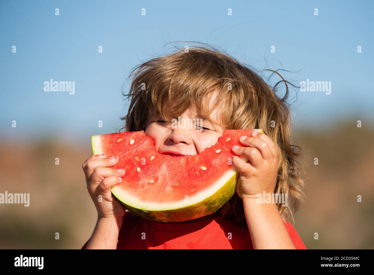 Kids with hungry face eating red watermelon in mouth. Child eat melon ...