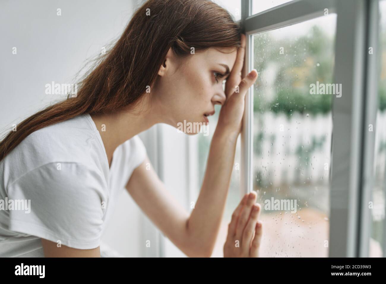 Sad woman looks out the windows interior loneliness Stock Photo - Alamy