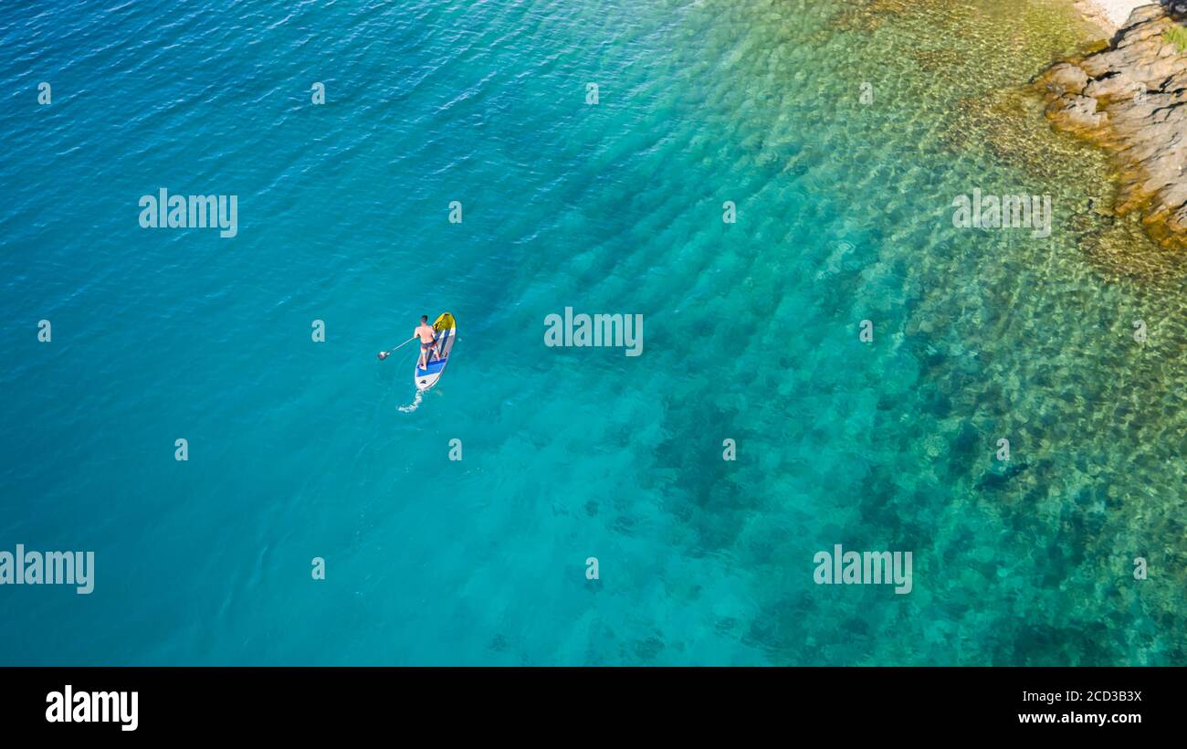 Aerial view of young man riding paddleboard. Paddleboarding is the ...