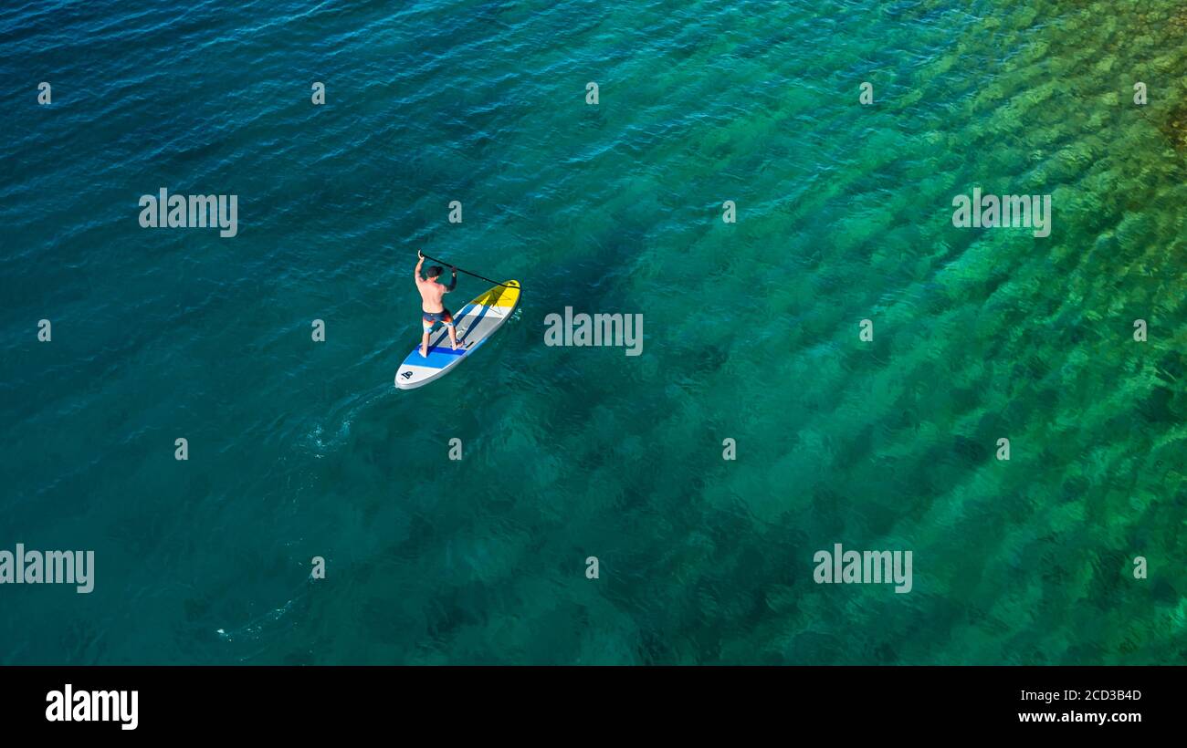 Aerial view of young man riding paddleboard. Paddleboarding is the ...