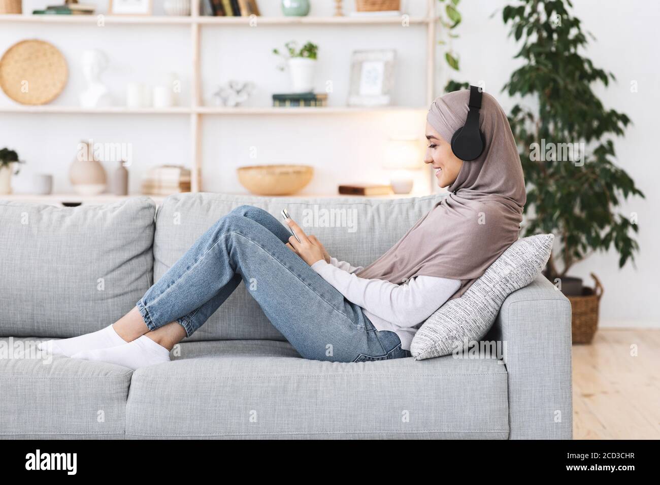Weekend Pastime. Arabic girl relaxing at home with smartphone and ...