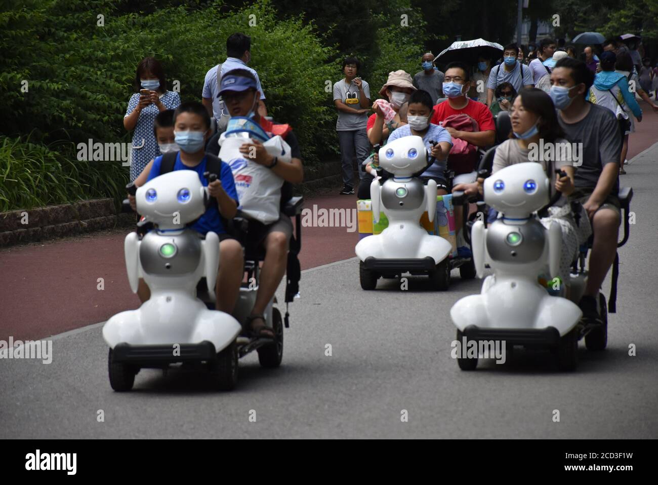 People ride on the robots designed for tour guide at the Olympic Forest ...