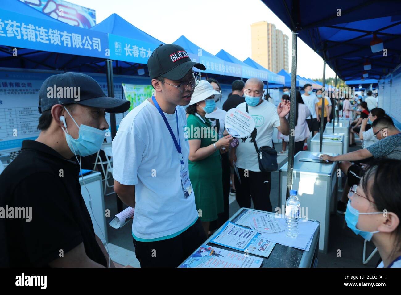 People inquire by a company consultation desk at a job fair and night ...