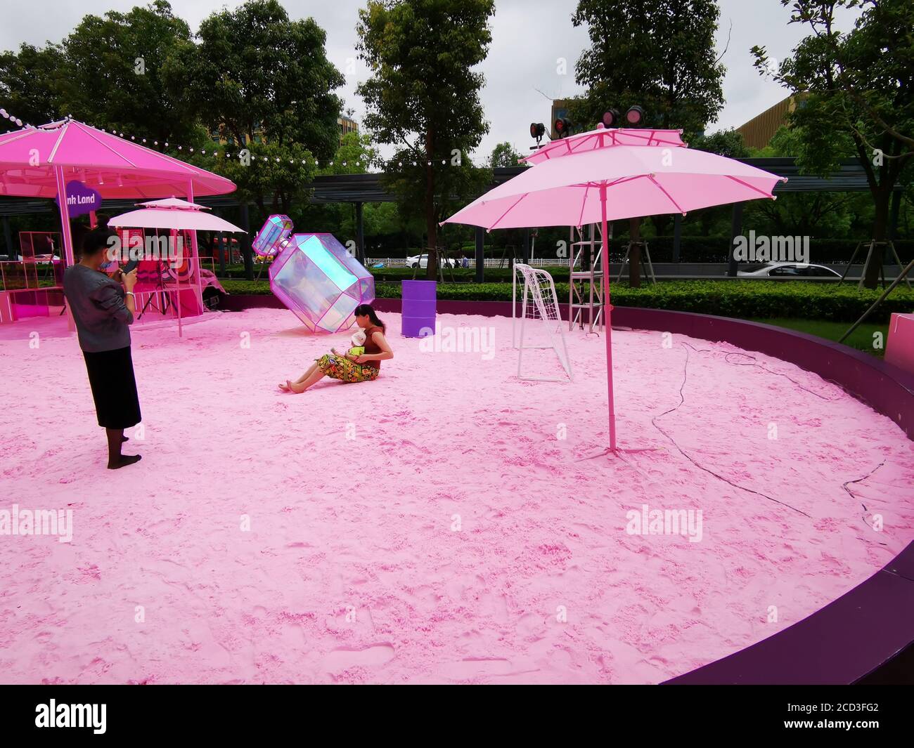 Customers play around the pink beach, which is composed of pink sands ...