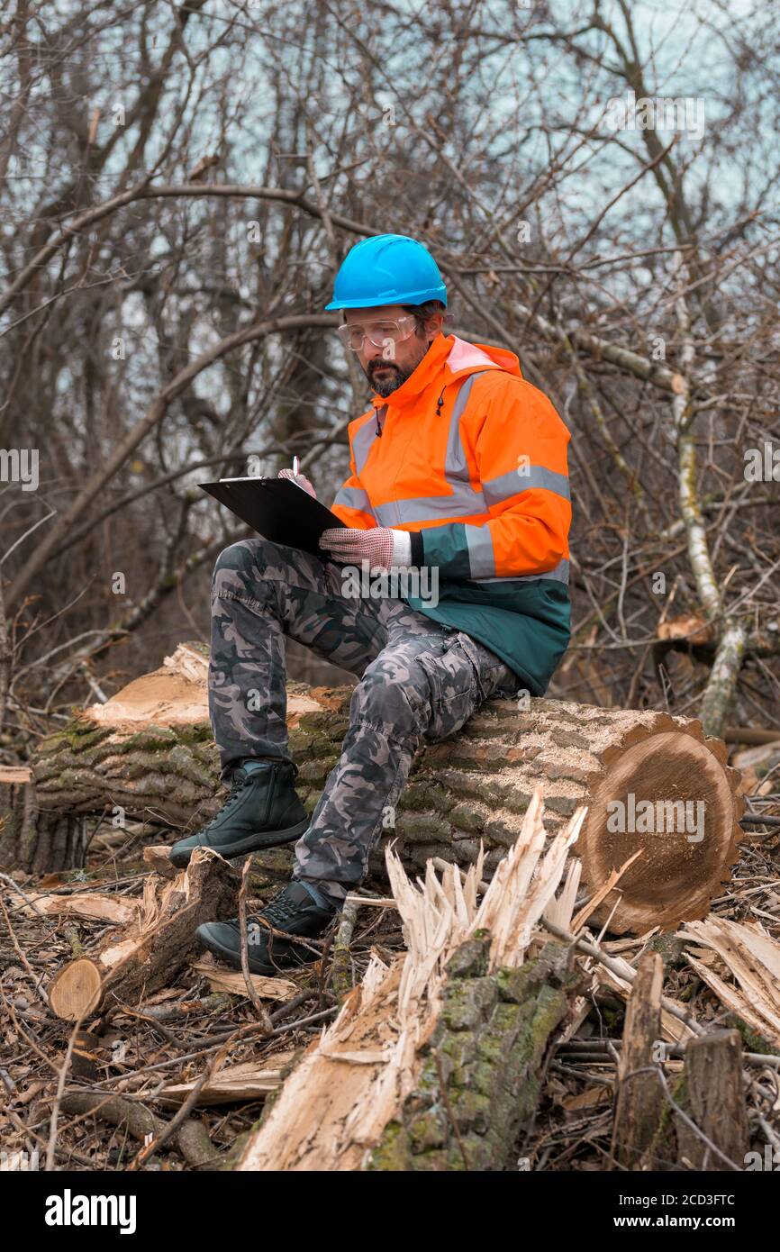 Forestry technician writing notes on clipboard notepad paper in forest ...