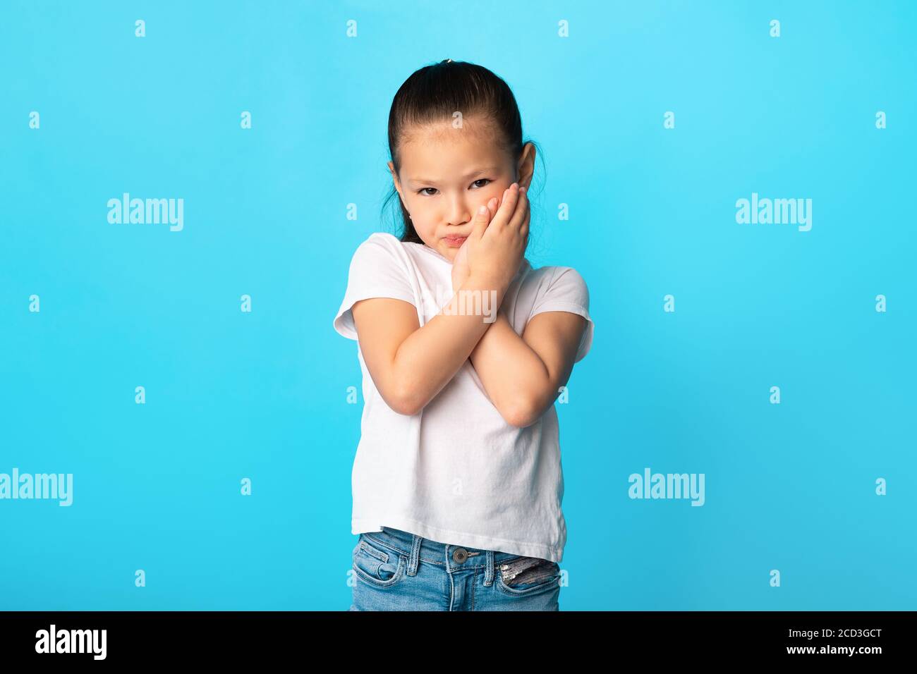 Adorable asian girl touching her cheek at studio Stock Photo - Alamy