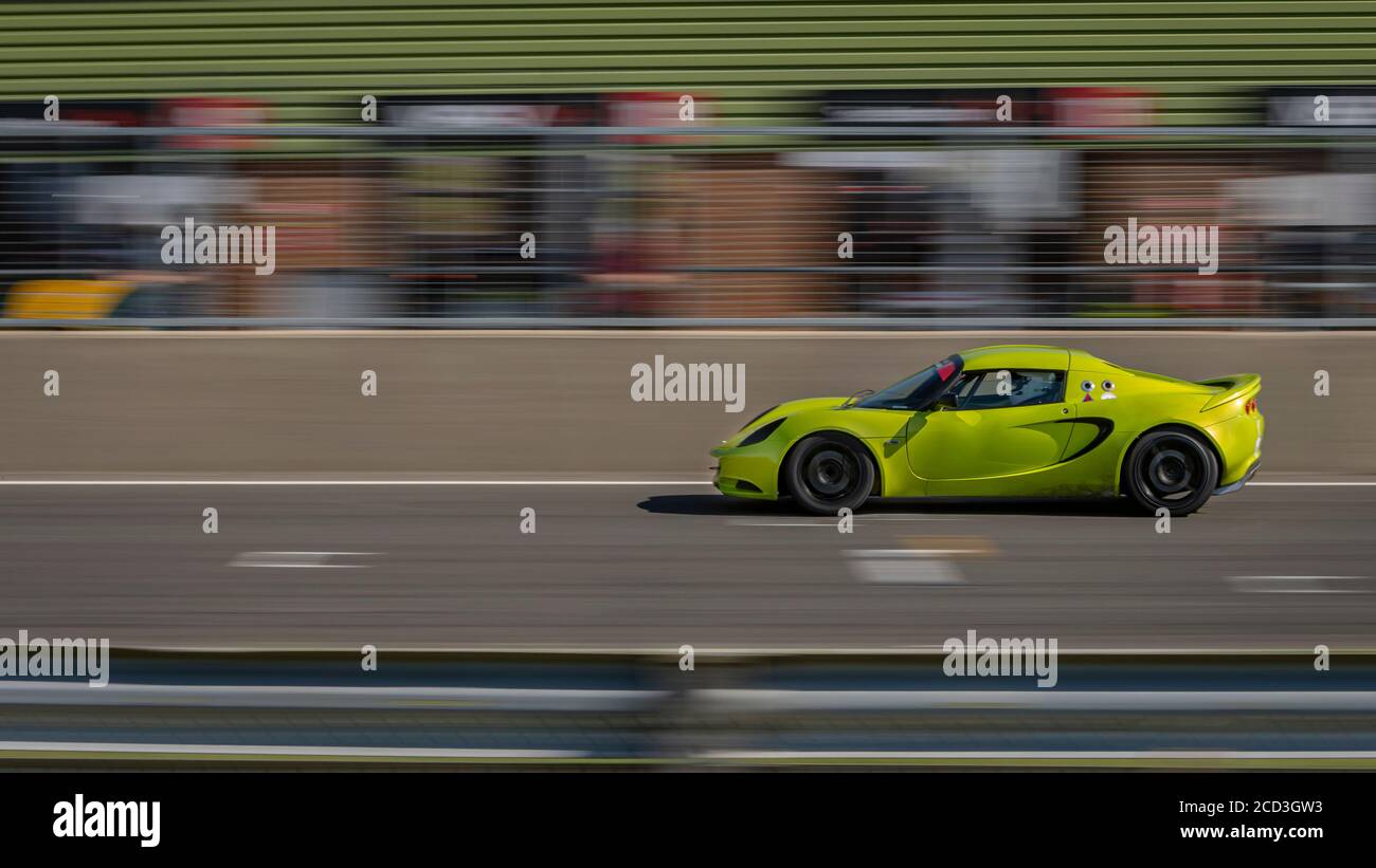 A panning shot of a green racing car as it circuits a track Stock Photo ...