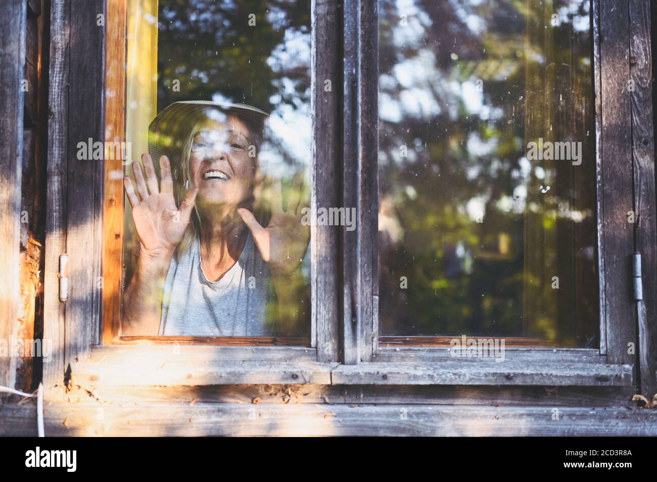 Happy smiling emotional elderly woman having fun posing by open window ...