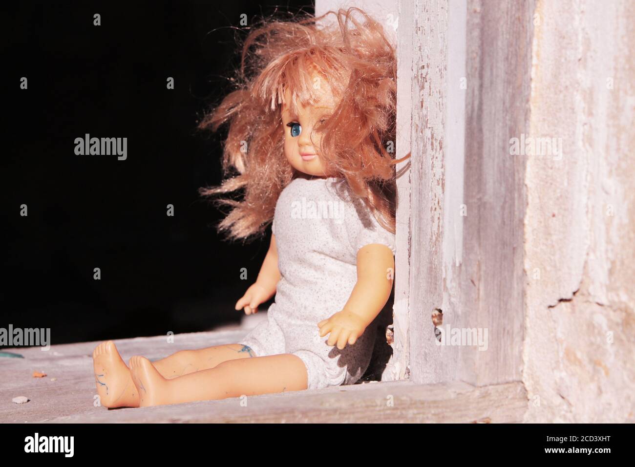 abandoned doll sitting on a window frame of an abandoned building ...
