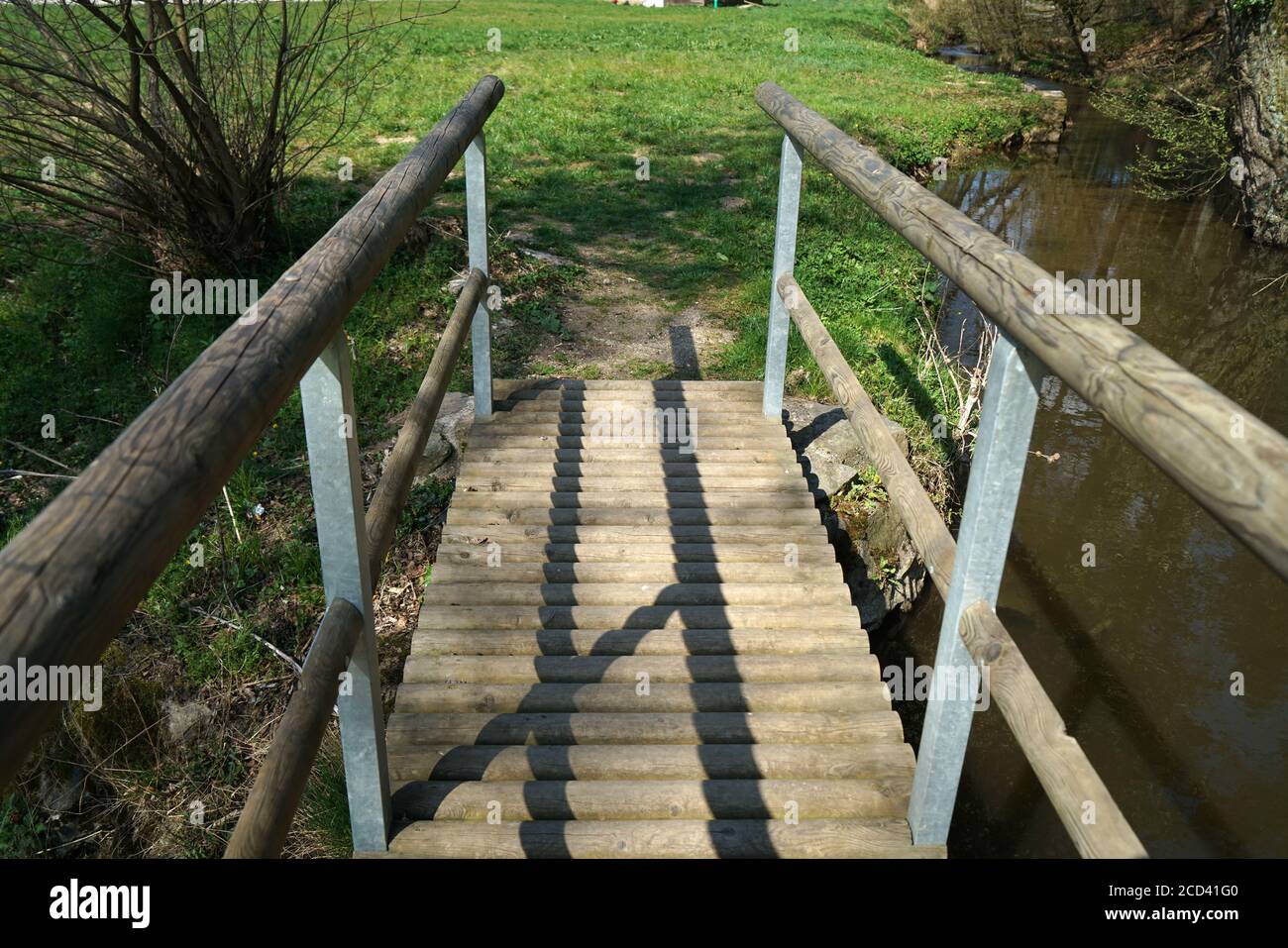 Narrow wooden bridge over a river in a park Stock Photo - Alamy