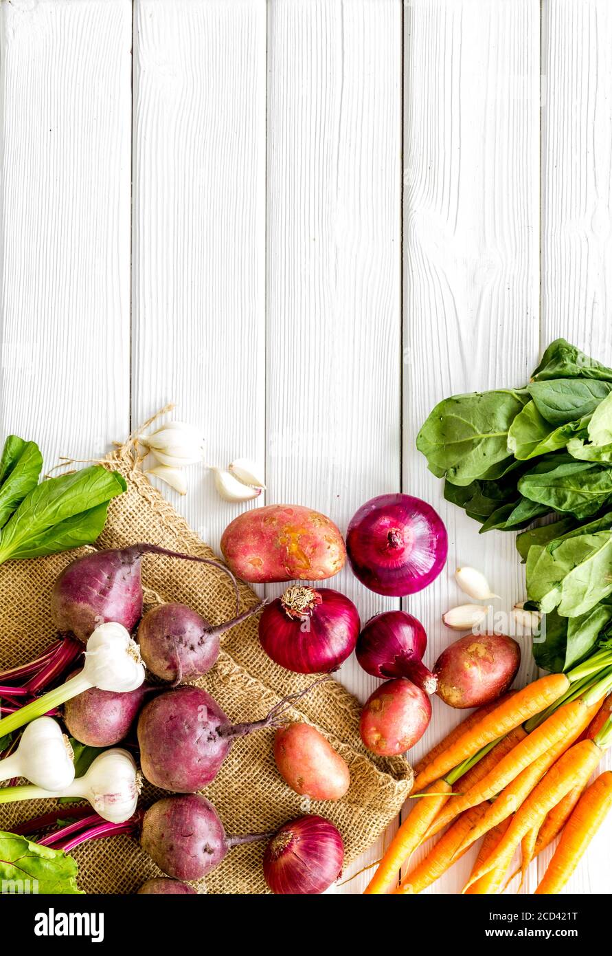 Flat lay of fresh vegetables and greenery on white table top-down copy ...