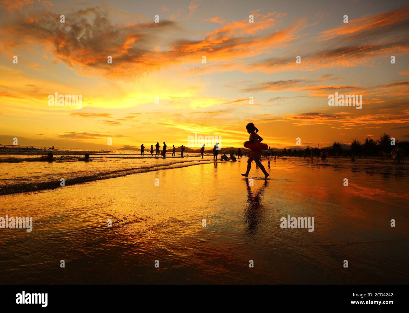 People play by the beach at Sanya Bay against the sunset in Sanya city ...
