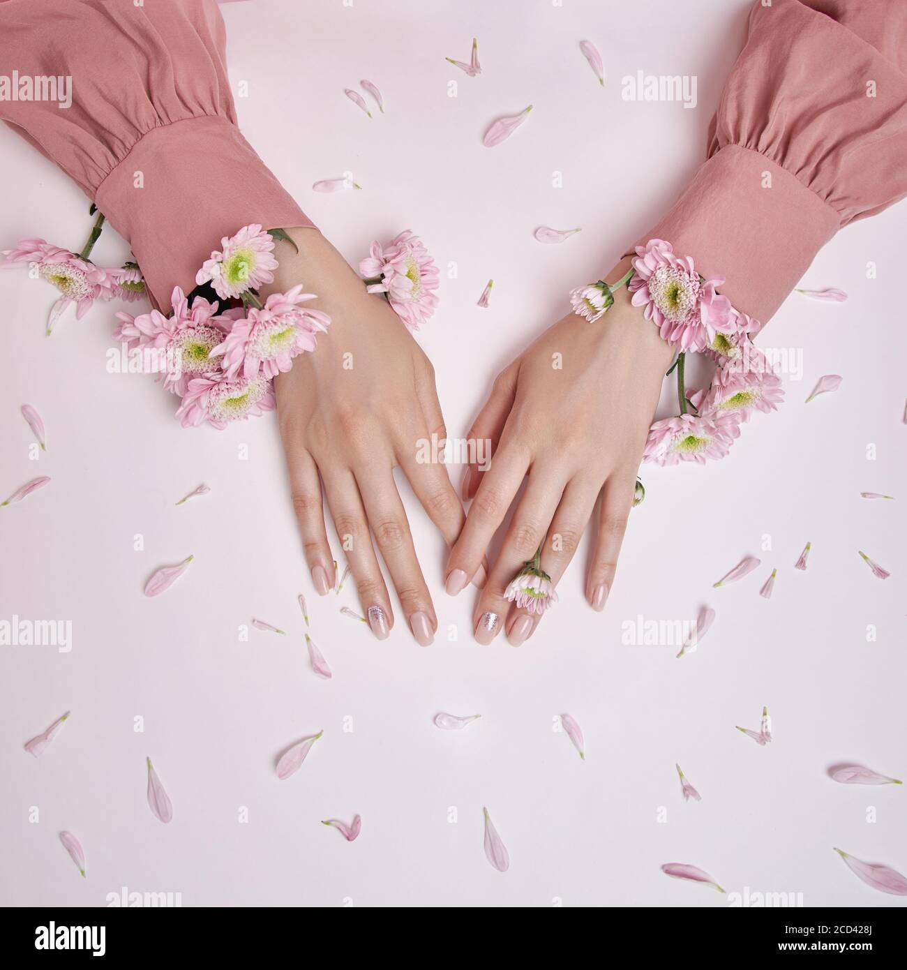 Beauty hands woman with pink flowers are on the table. Natural cosmetic ...