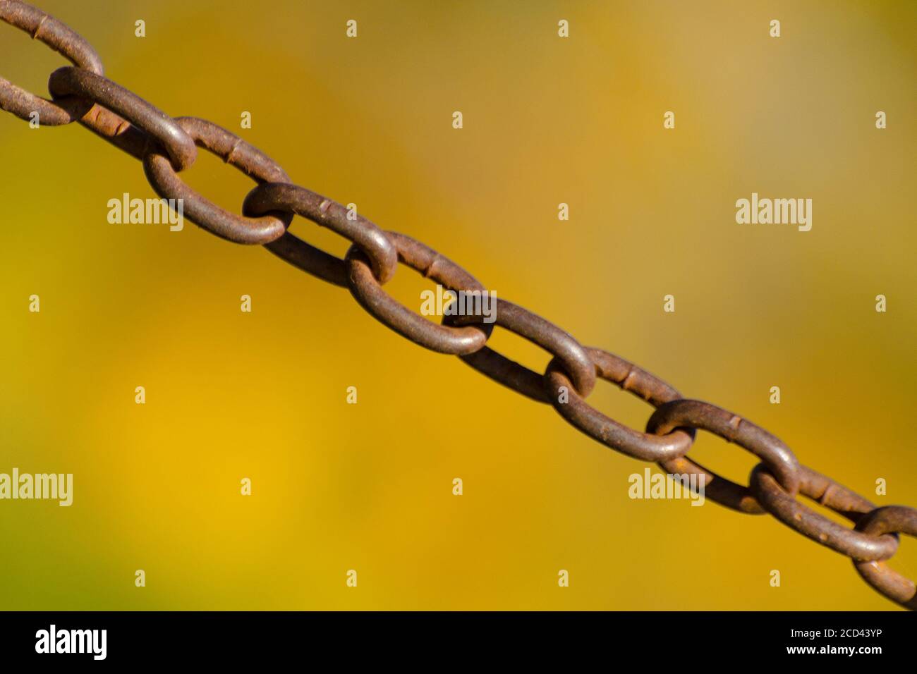 Old metal chain on a blurred yellow background Stock Photo - Alamy