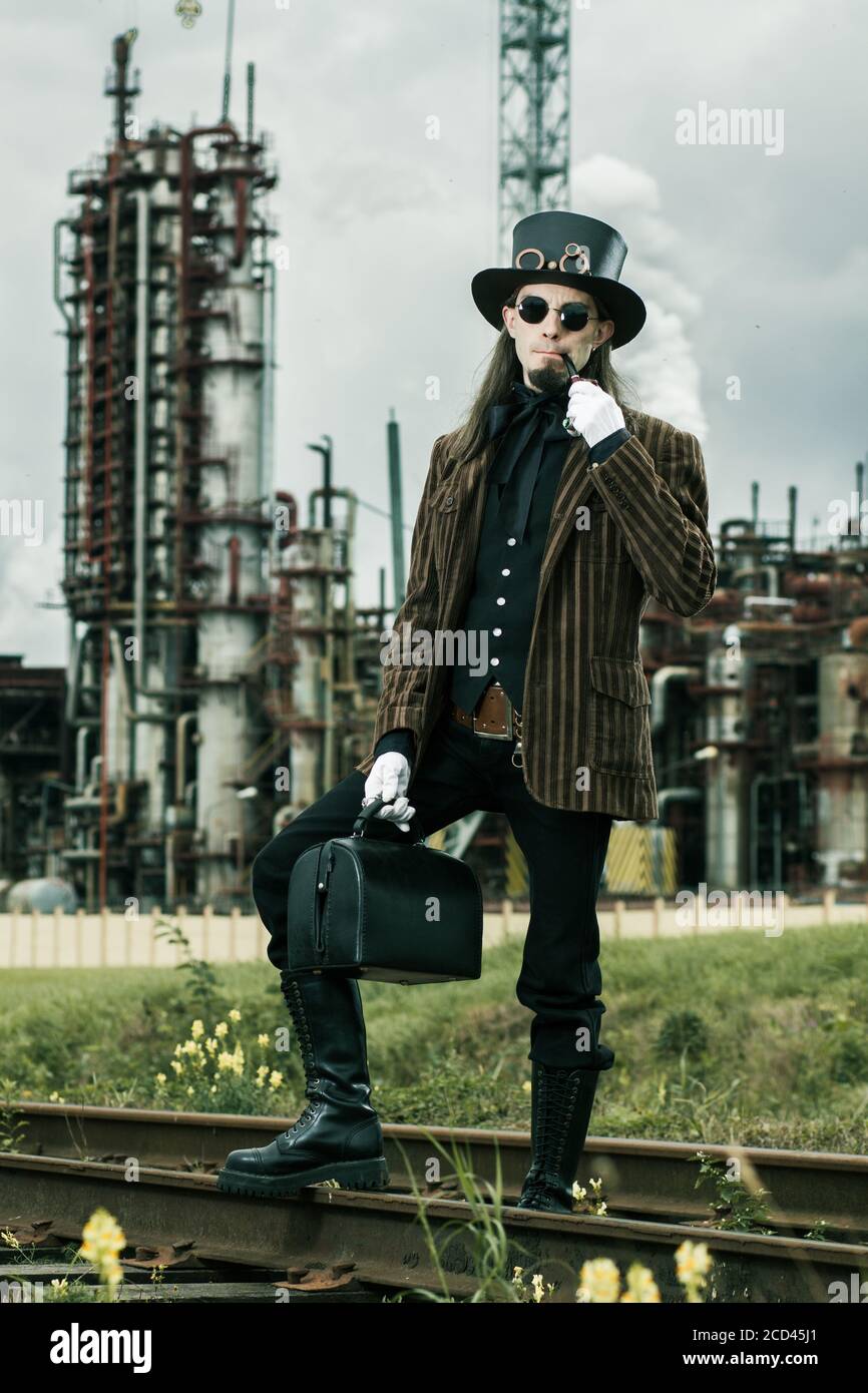 Young man weared in steampunk style posing on industrial background ...