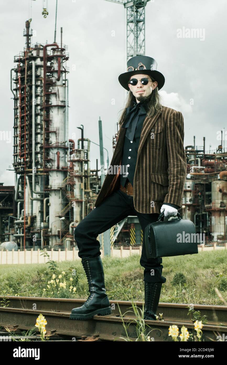 Young man weared in steampunk style posing on industrial background ...