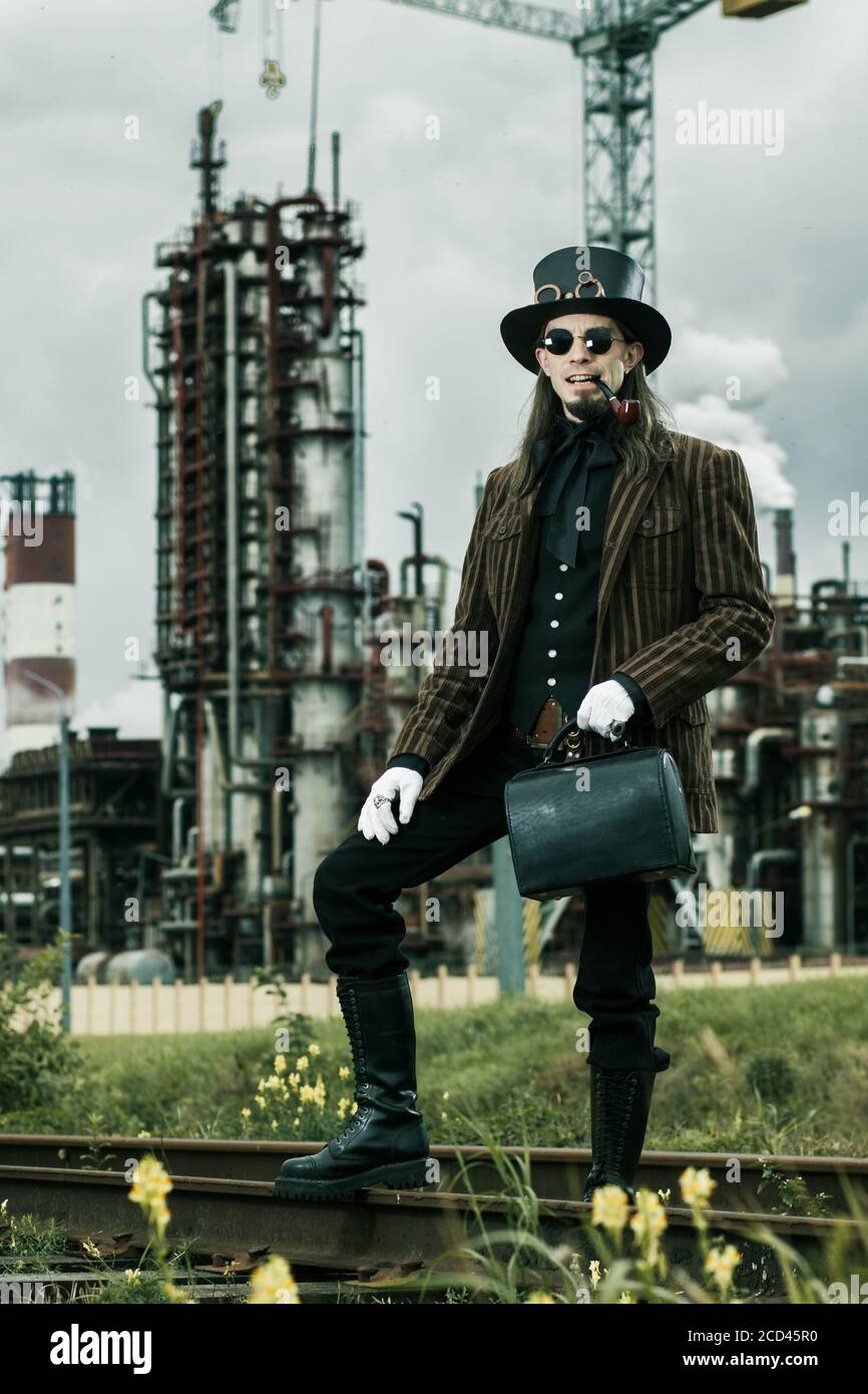 Young man weared in steampunk style posing on industrial background ...