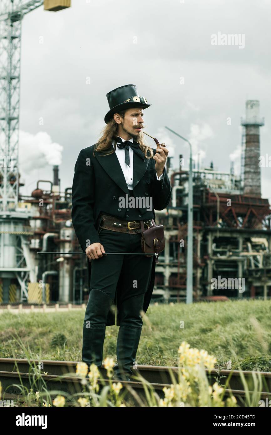 Young man weared in steampunk style posing on industrial background ...