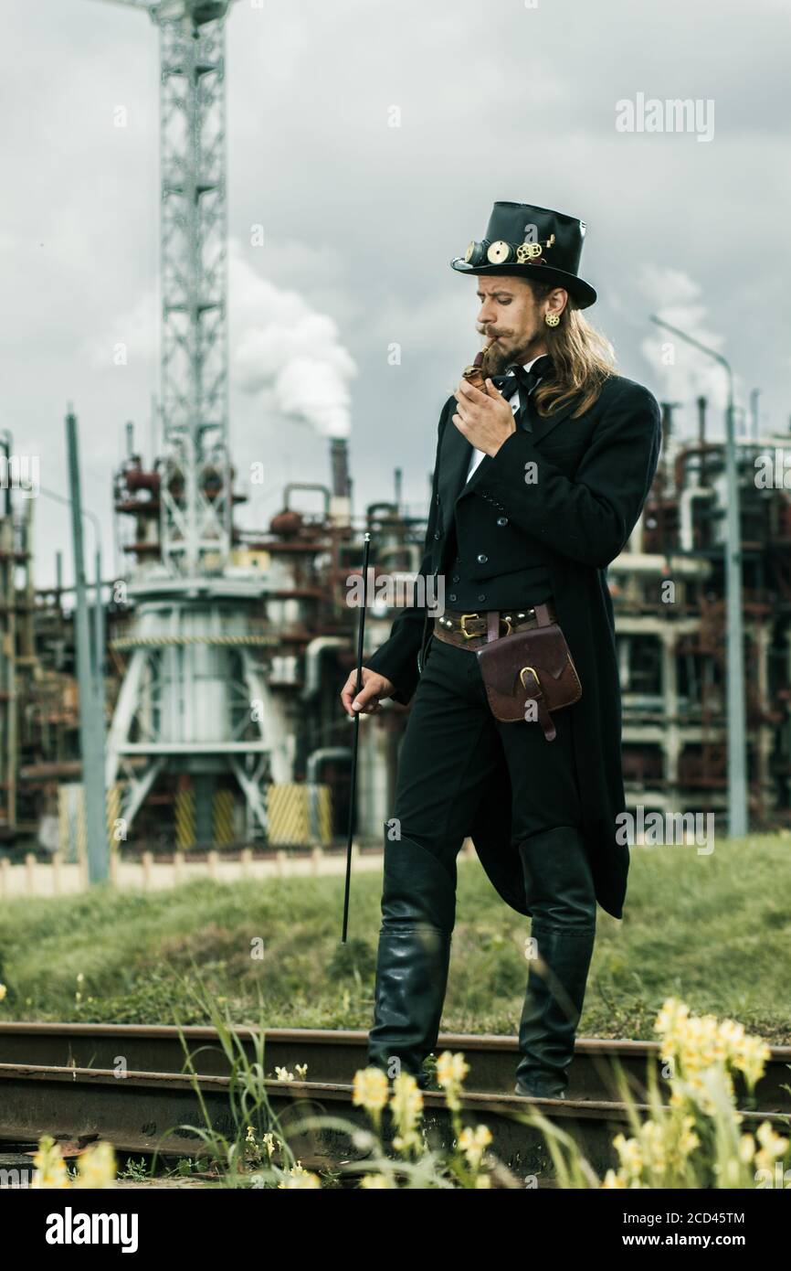 Young man weared in steampunk style posing on industrial background ...