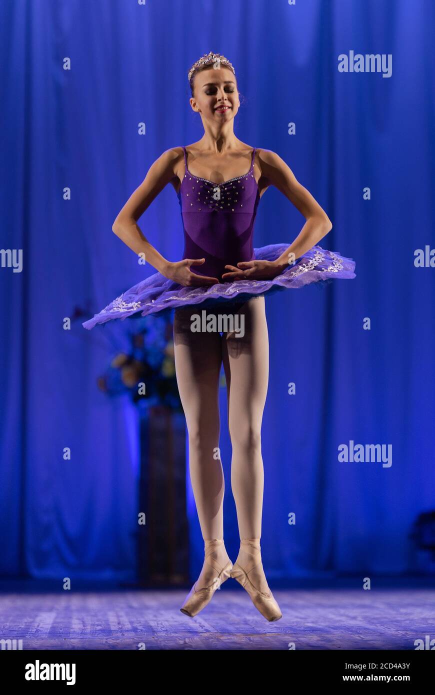 Young girl ballerina in a purple tutu dancing performance on stage in a ...