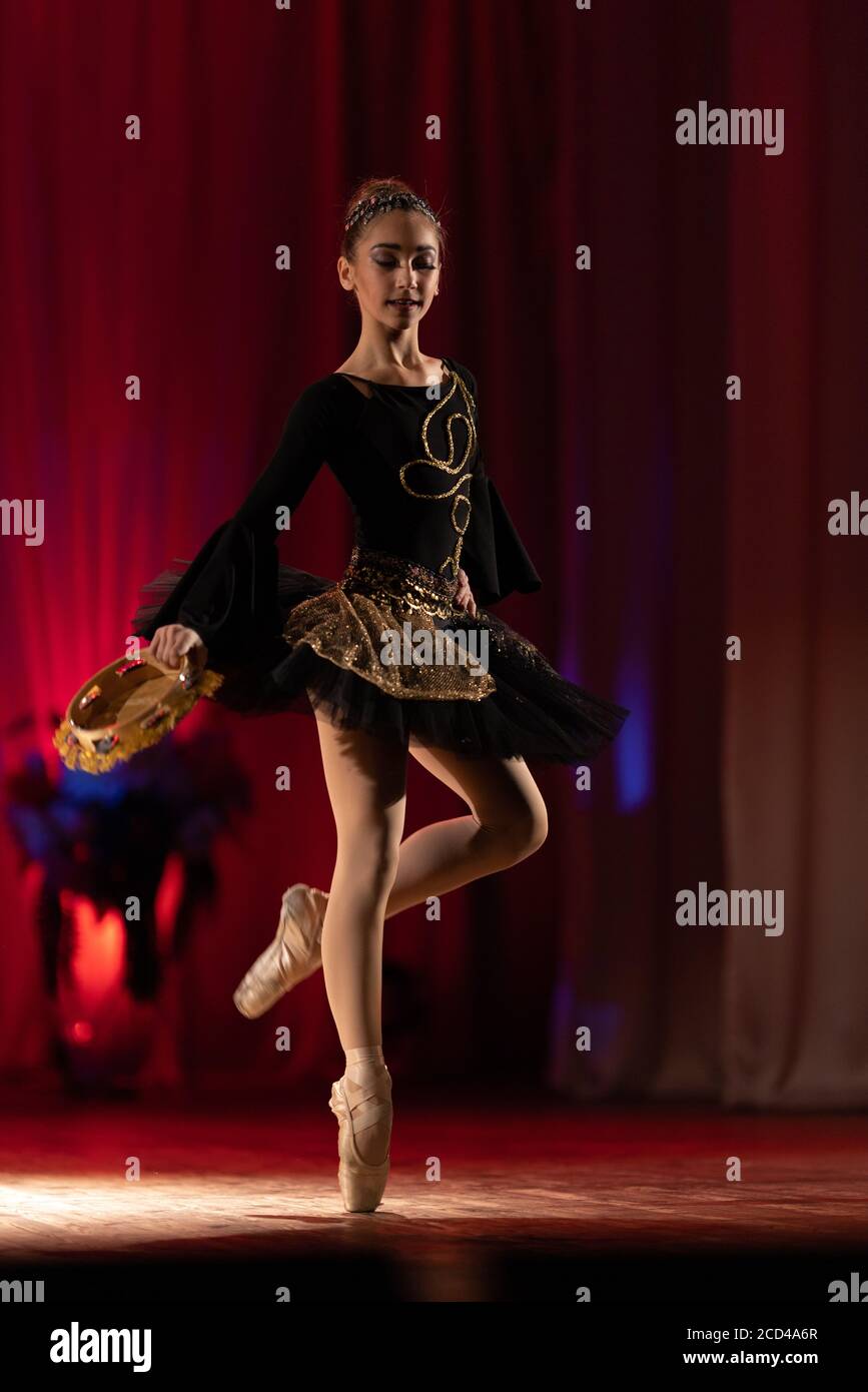Young girl ballerina in a black tutu dress dancing performance on stage ...