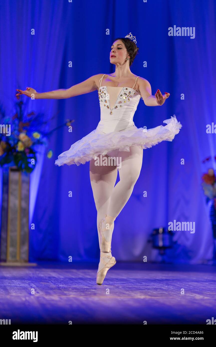Young woman ballerina in a white tutu dancing performance on stage in a ...