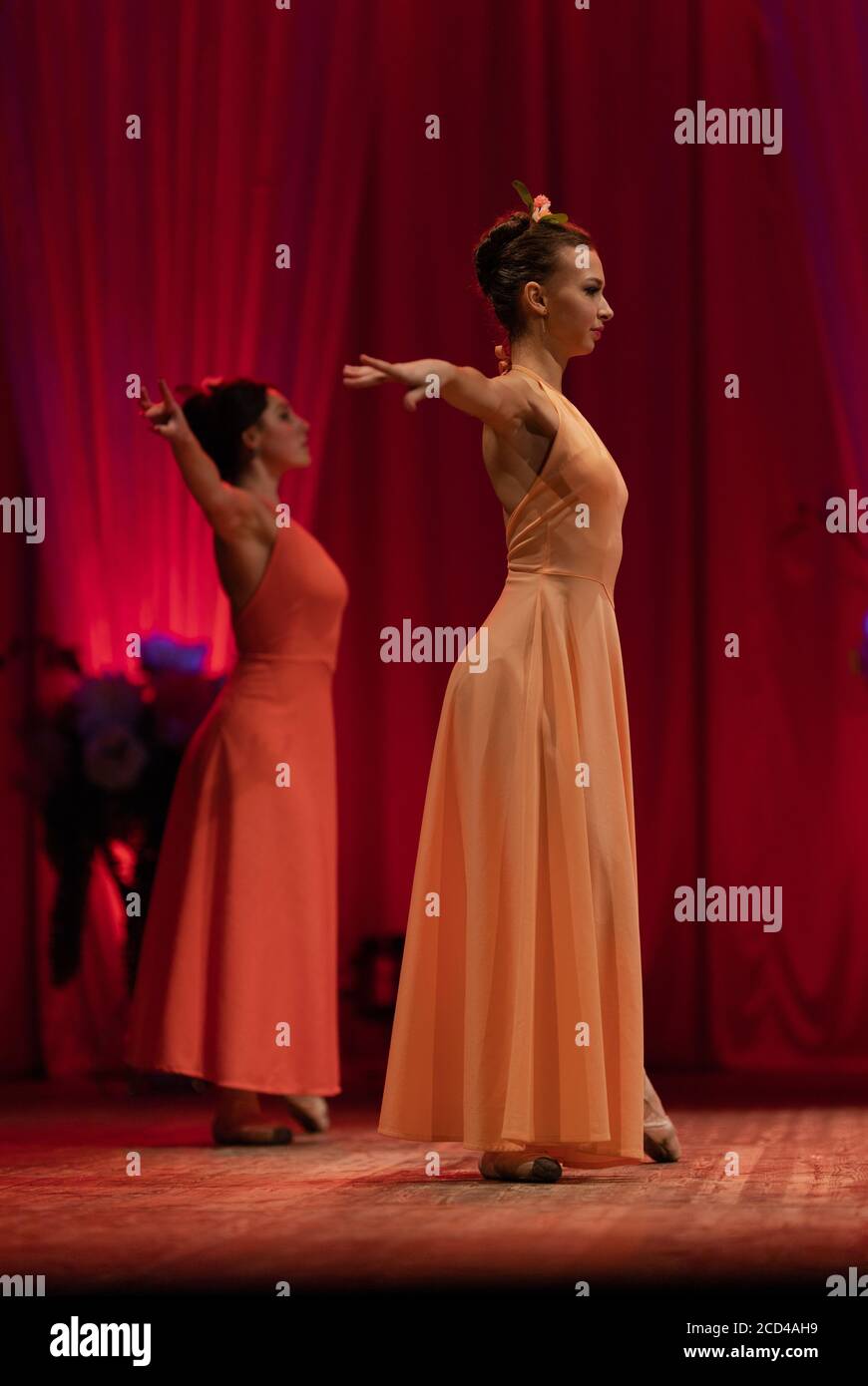 Young women ballerinas in yellow and orange long dresses perform a ...