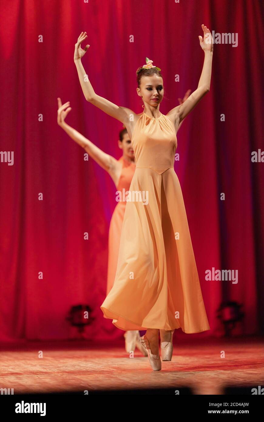 Young women ballerinas in yellow and orange long dresses perform a ...