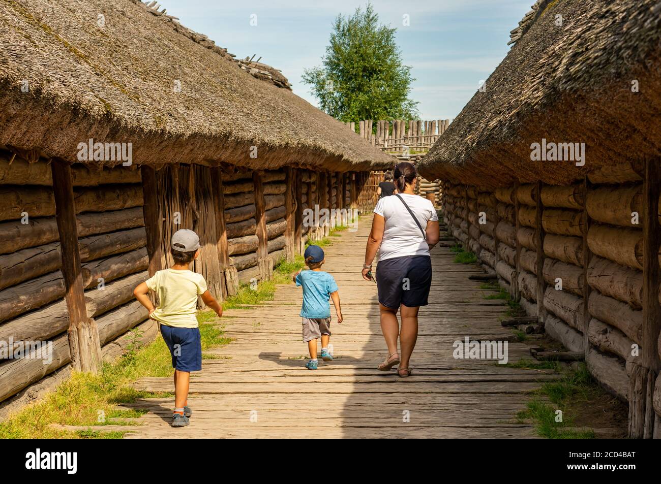 BISKUPIN, POLAND - Aug 20, 2020: Woman and two kids walking on a footpath along old wooden ...