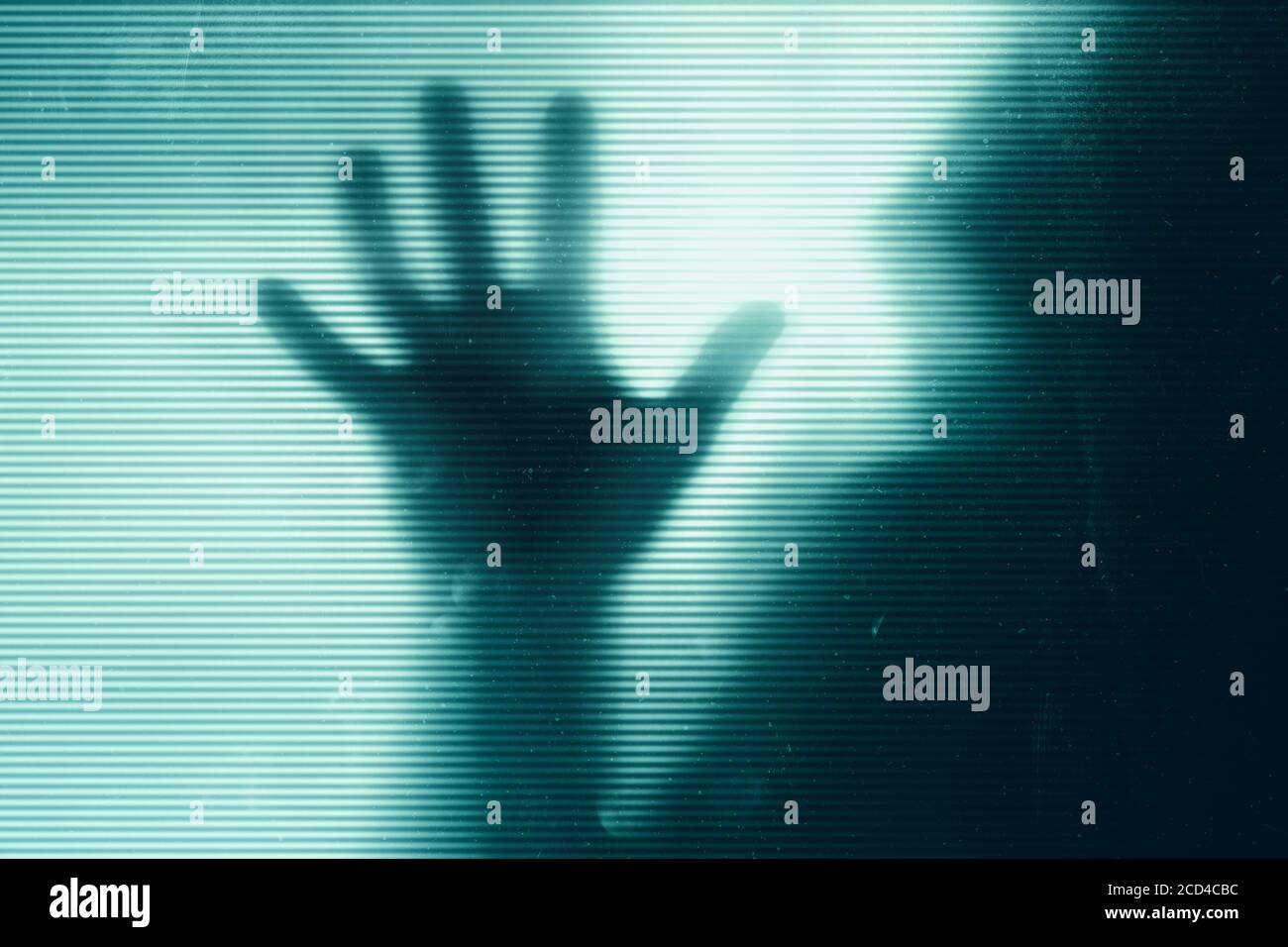 A spooky hooded figure holding his hand up looking through a TV screen ...