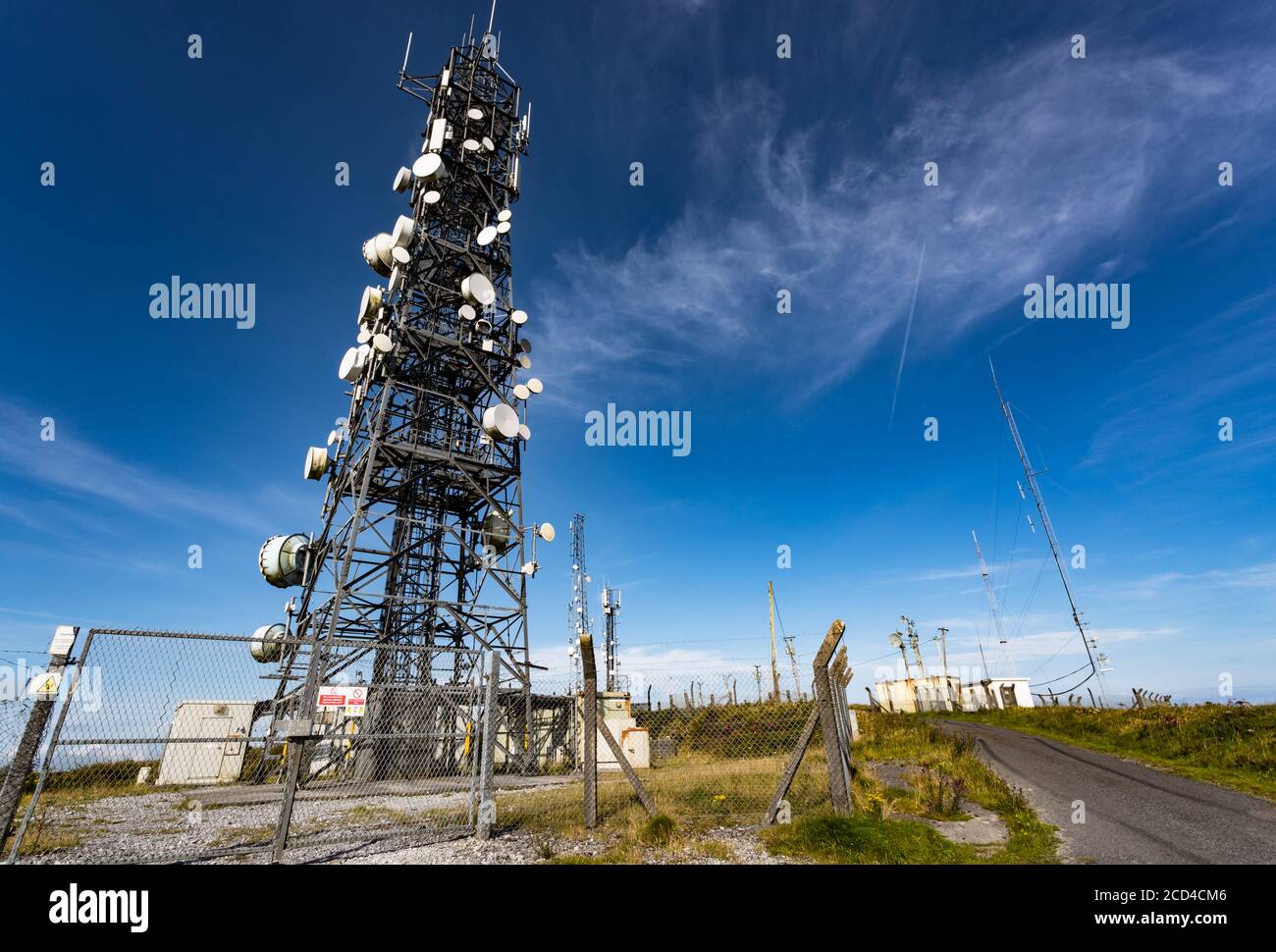 Telecommunication tower behind locked gate in rural area with blue sky ...