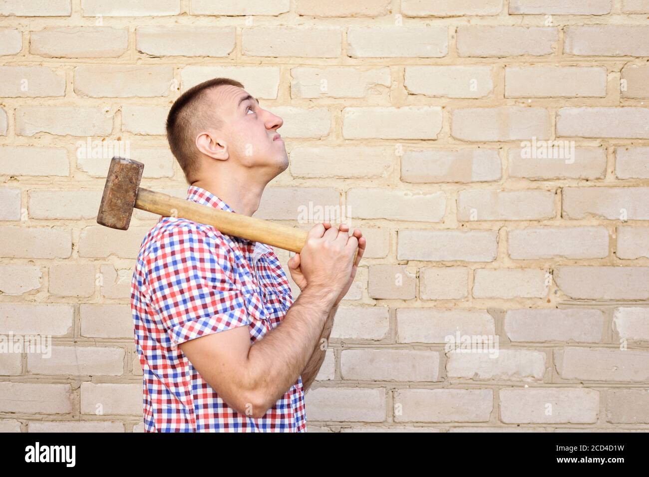 Man with a hammer on the shoulder, on the brick wall background ...