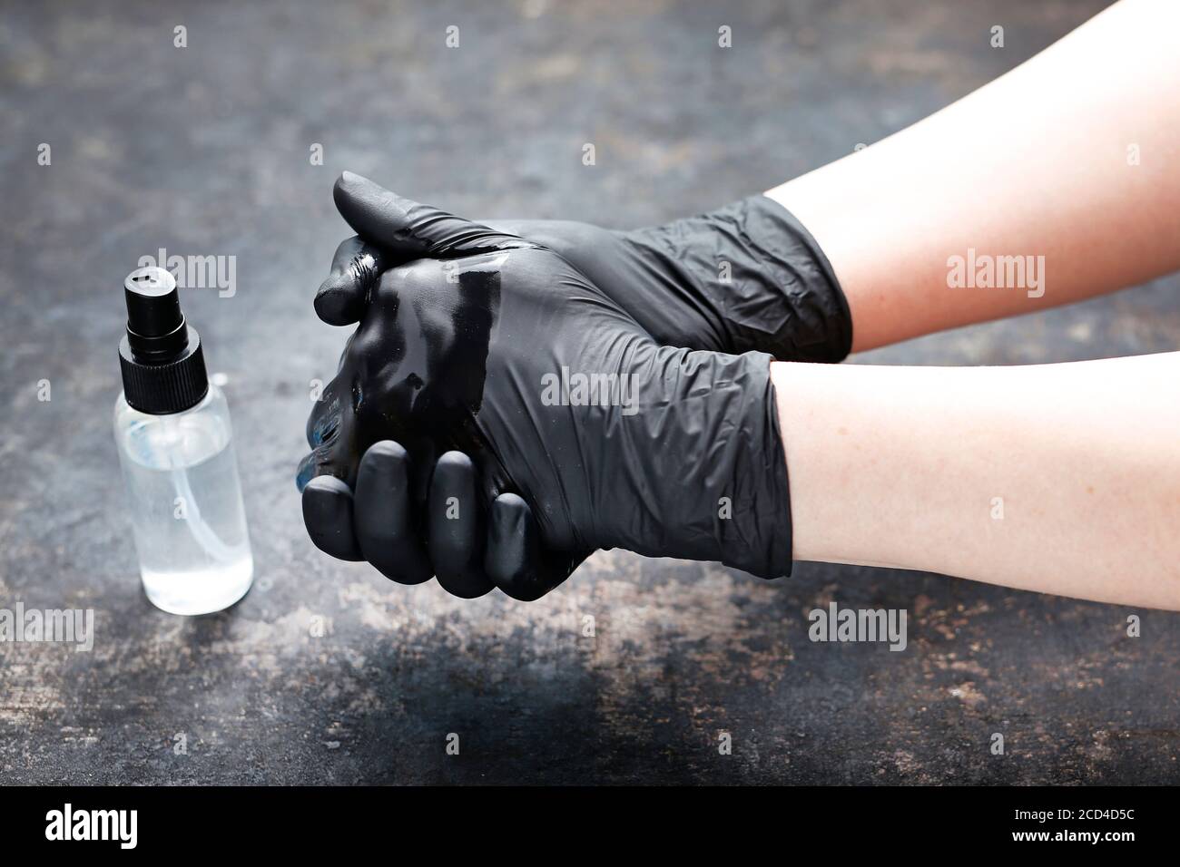 Hands in black protective gloves disinfected with antivirus fluid ...
