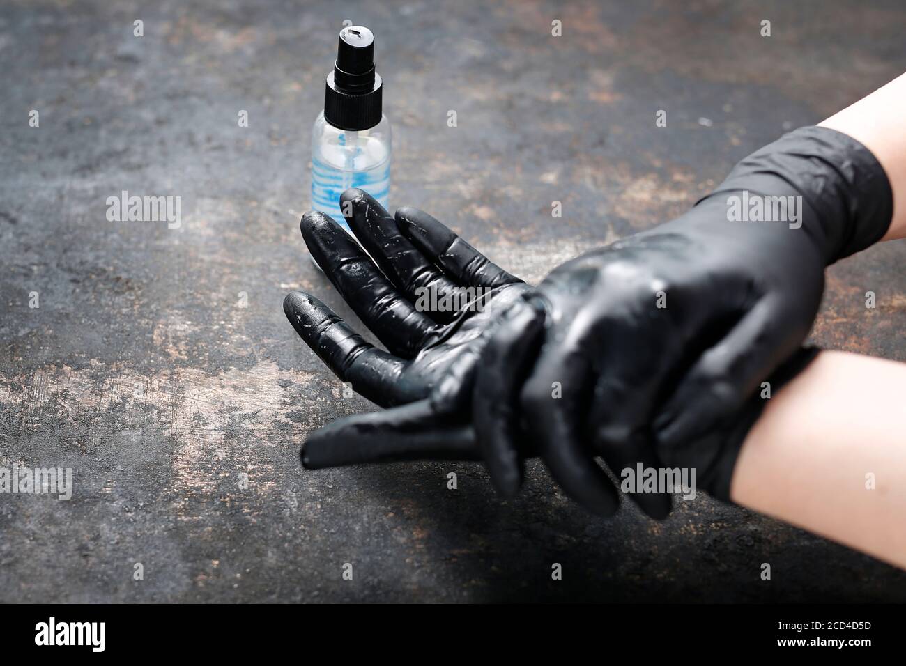 Hands in black protective gloves disinfected with antivirus fluid ...