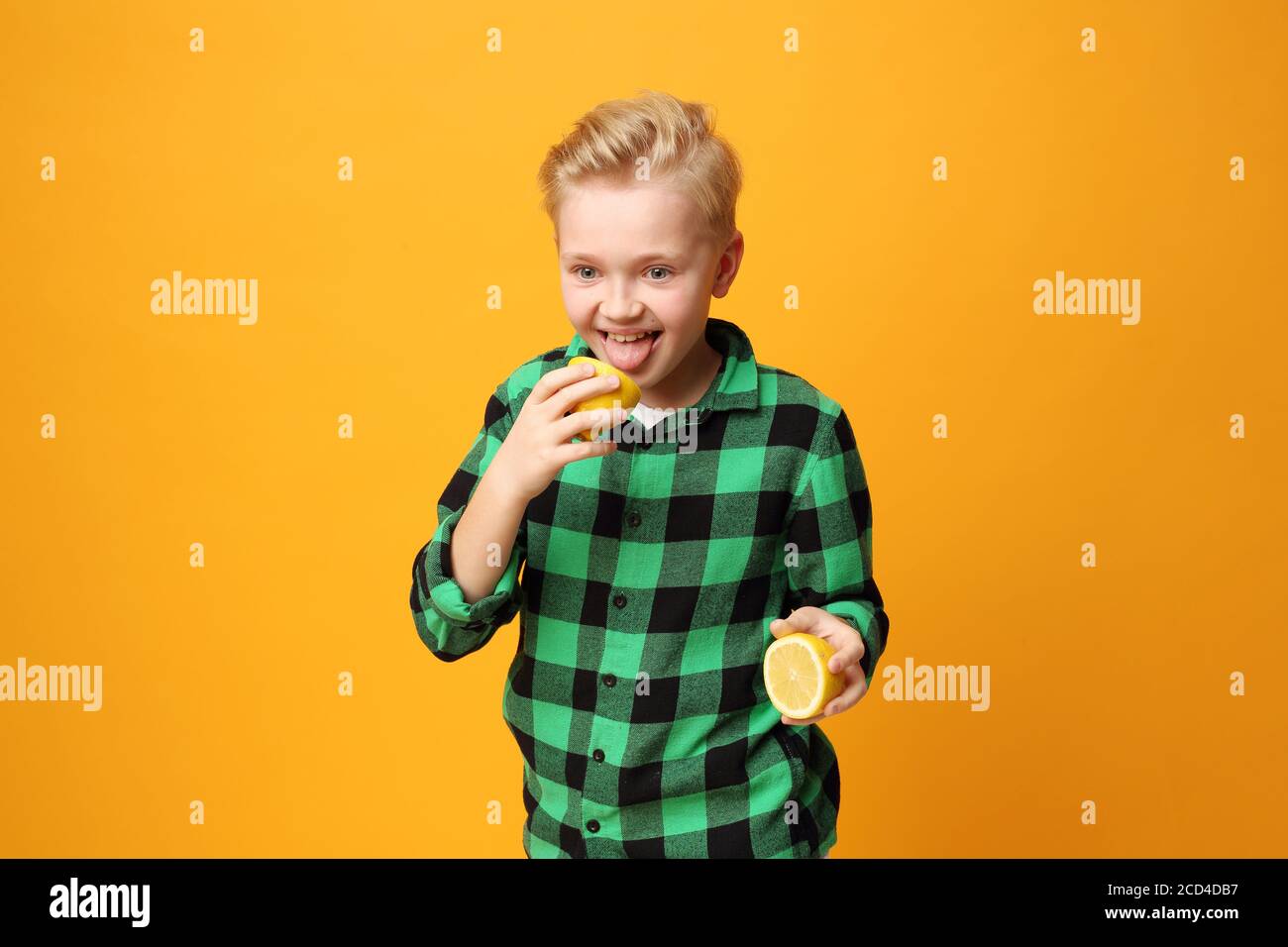 Sour face, cheerful facial expression. The boy bites a lemon. Happy ...