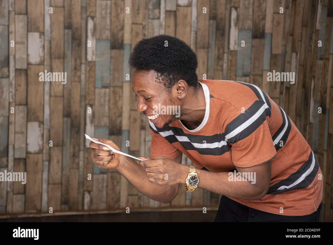 Happy young African man looking at a piece of paper Stock Photo - Alamy