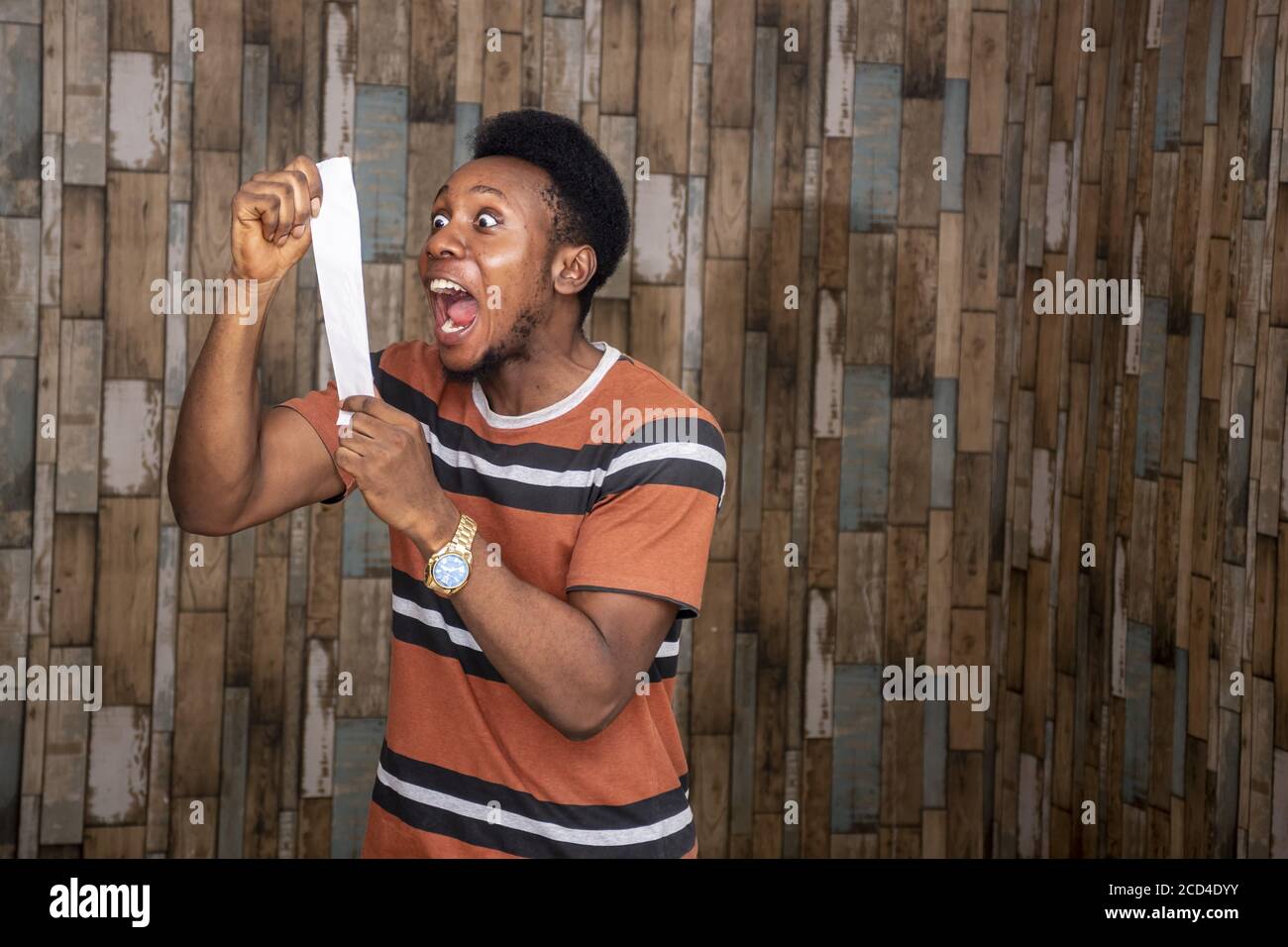 Young African male feeling excited and happy while holding a paper slip ...